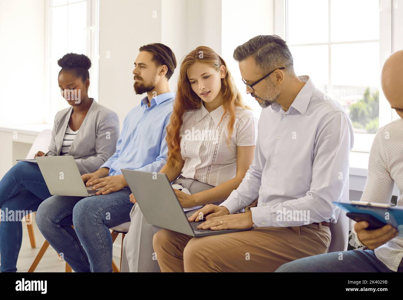 Diverse business people working on laptop computers while sitting in ...