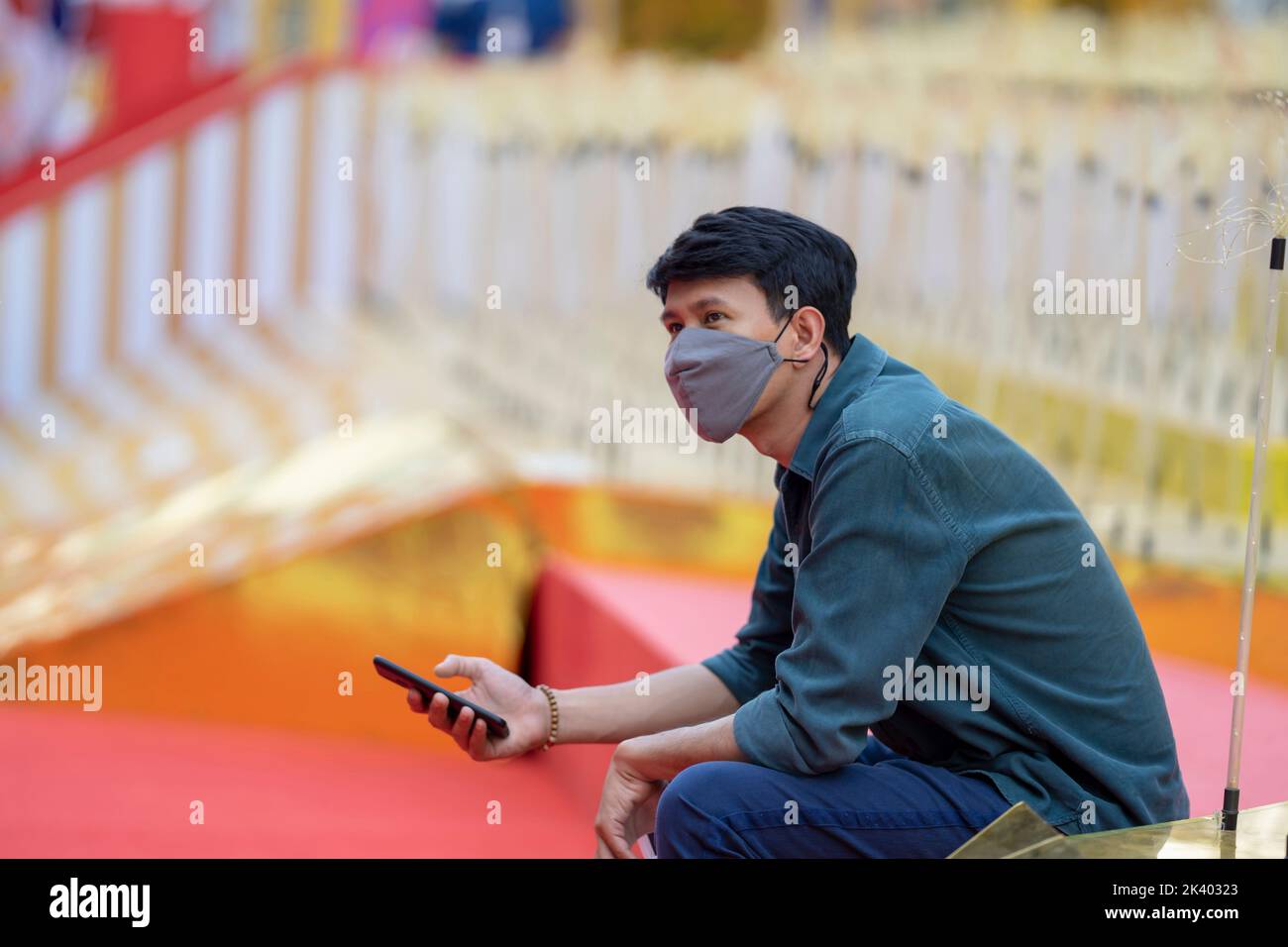 Asian Smart man in casual dark green shirt and gray cloth mask sit in ...