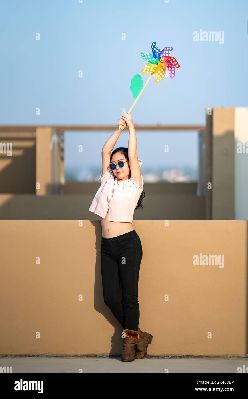 Asian woman posts and play Windmill Toy colourful rainbow colour on the ...