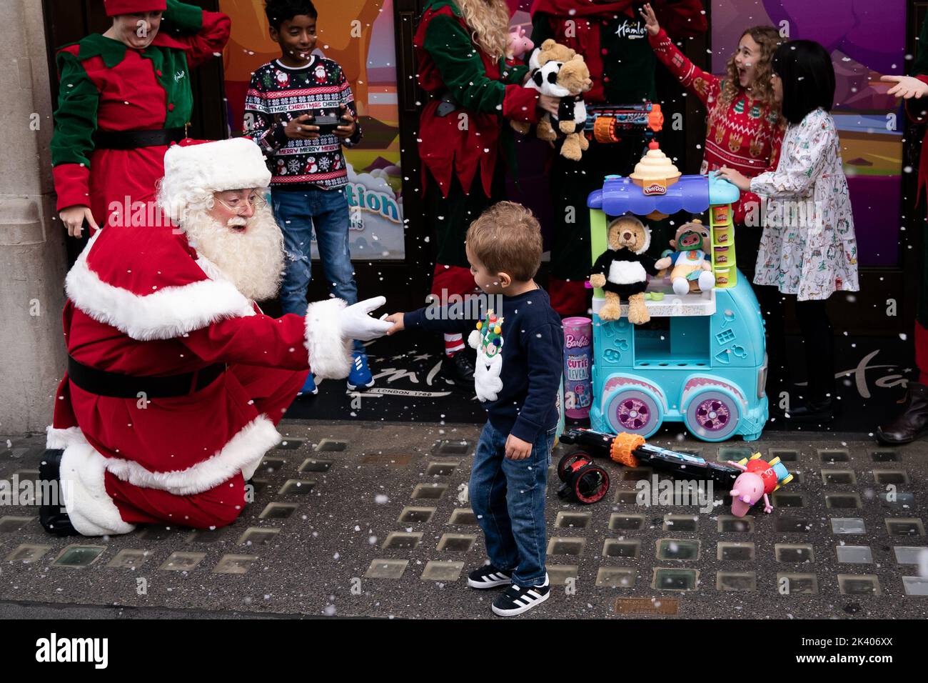 A child greets a man dressed as Santa Claus as they attend the Hamleys ...