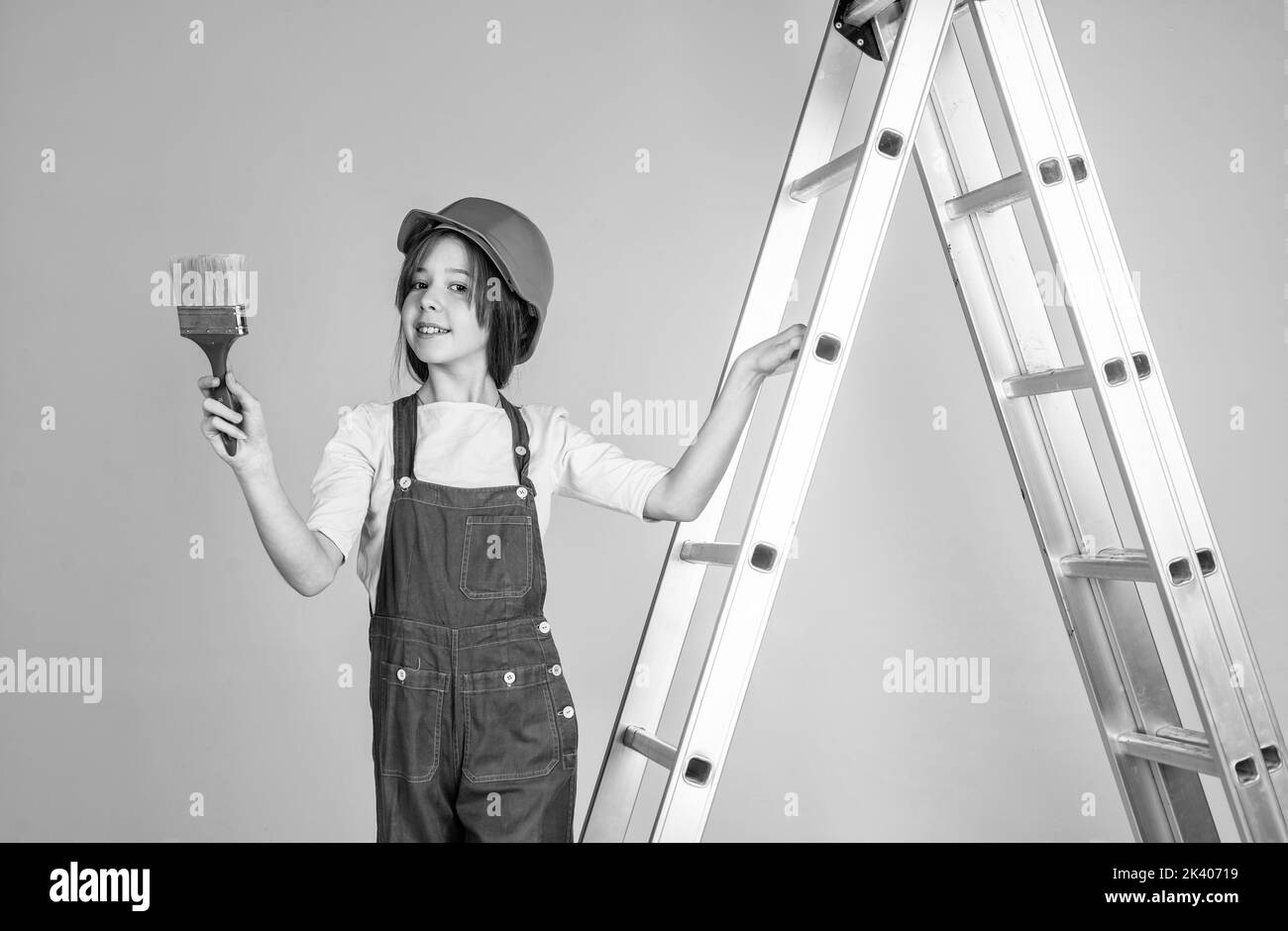teen girl laborer in protective helmet and uniform on ladder with ...