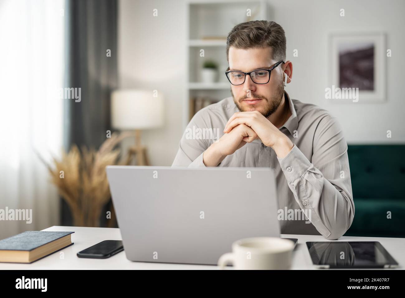 Thoughtful handsome man coding from home at laptop, remote work concept ...