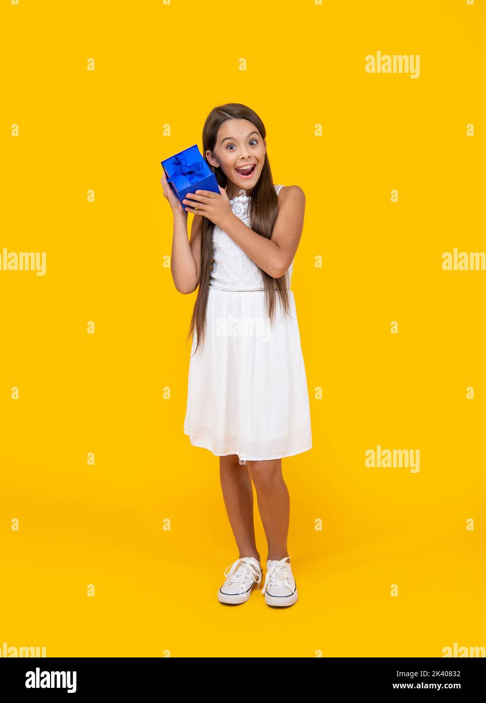 surprised teen girl hold present box on yellow background Stock Photo ...