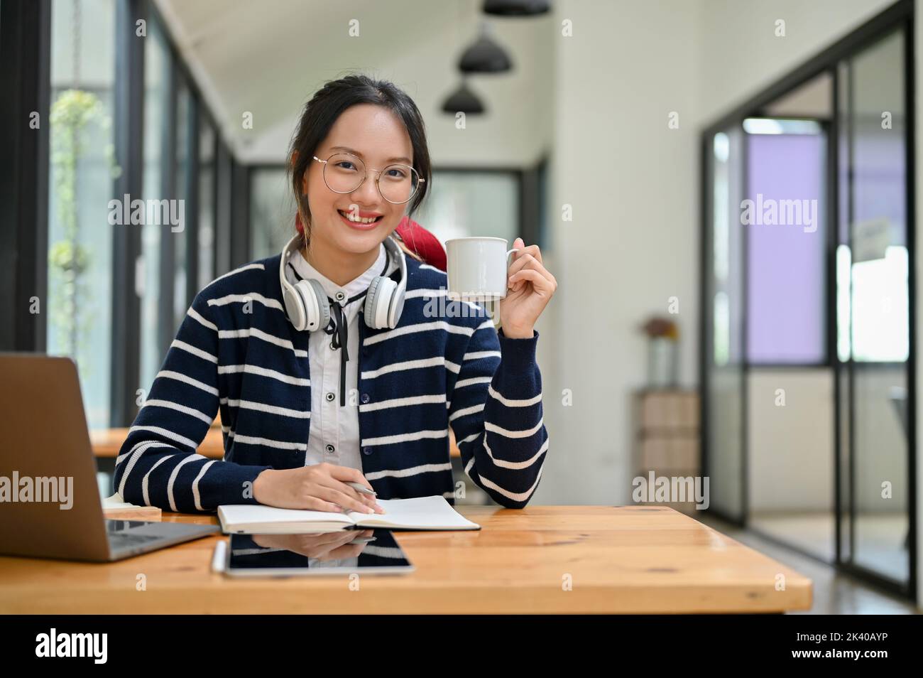 Beautiful and happy young Asian female student sipping coffee while ...