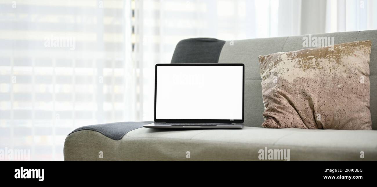 Notebook laptop computer white screen mockup is on a comfortable sofa ...