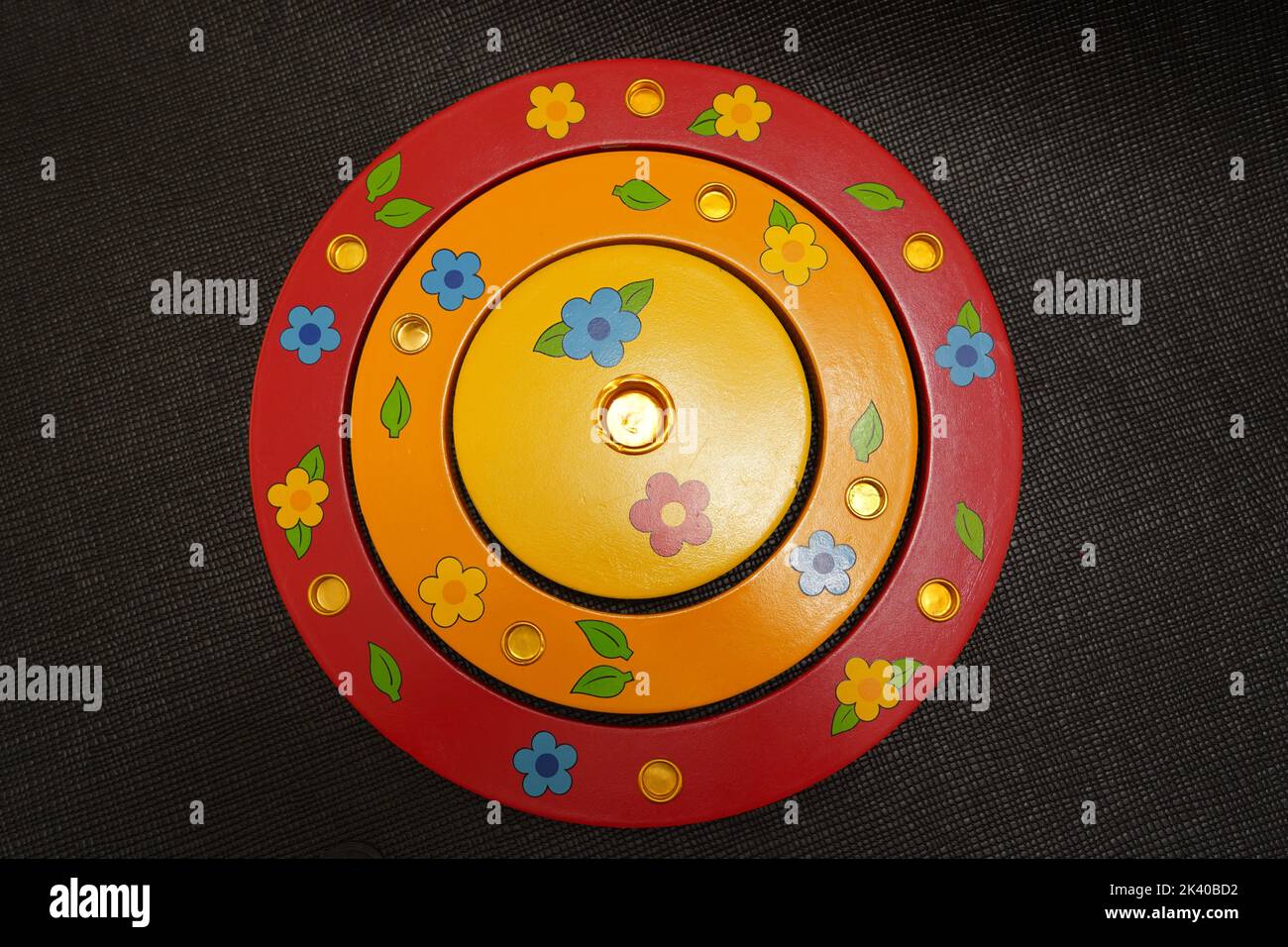 toy rings with yellow wooden flowers over textured black background ...