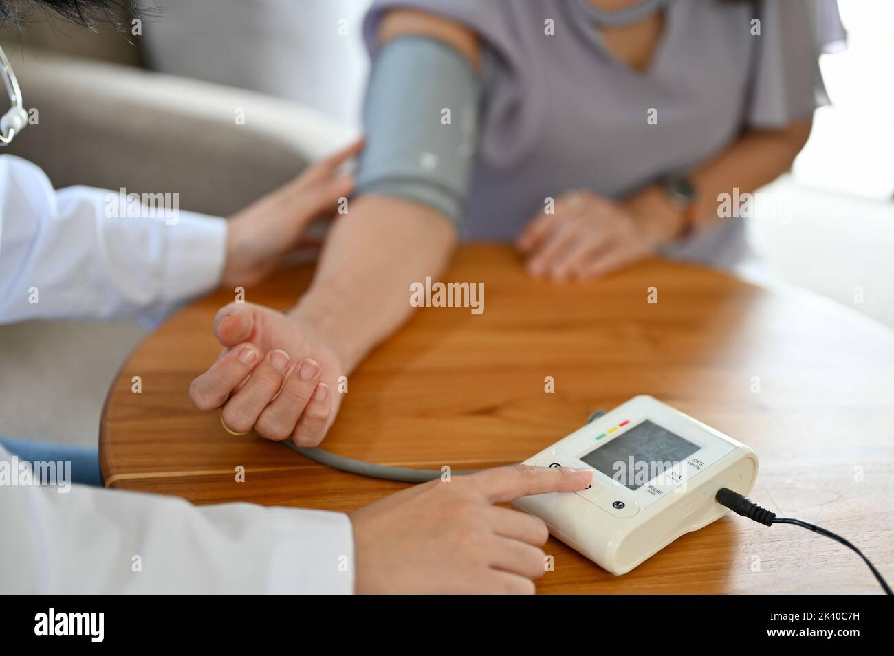 A female doctor or nurse checking patient's blood pressure and heart ...