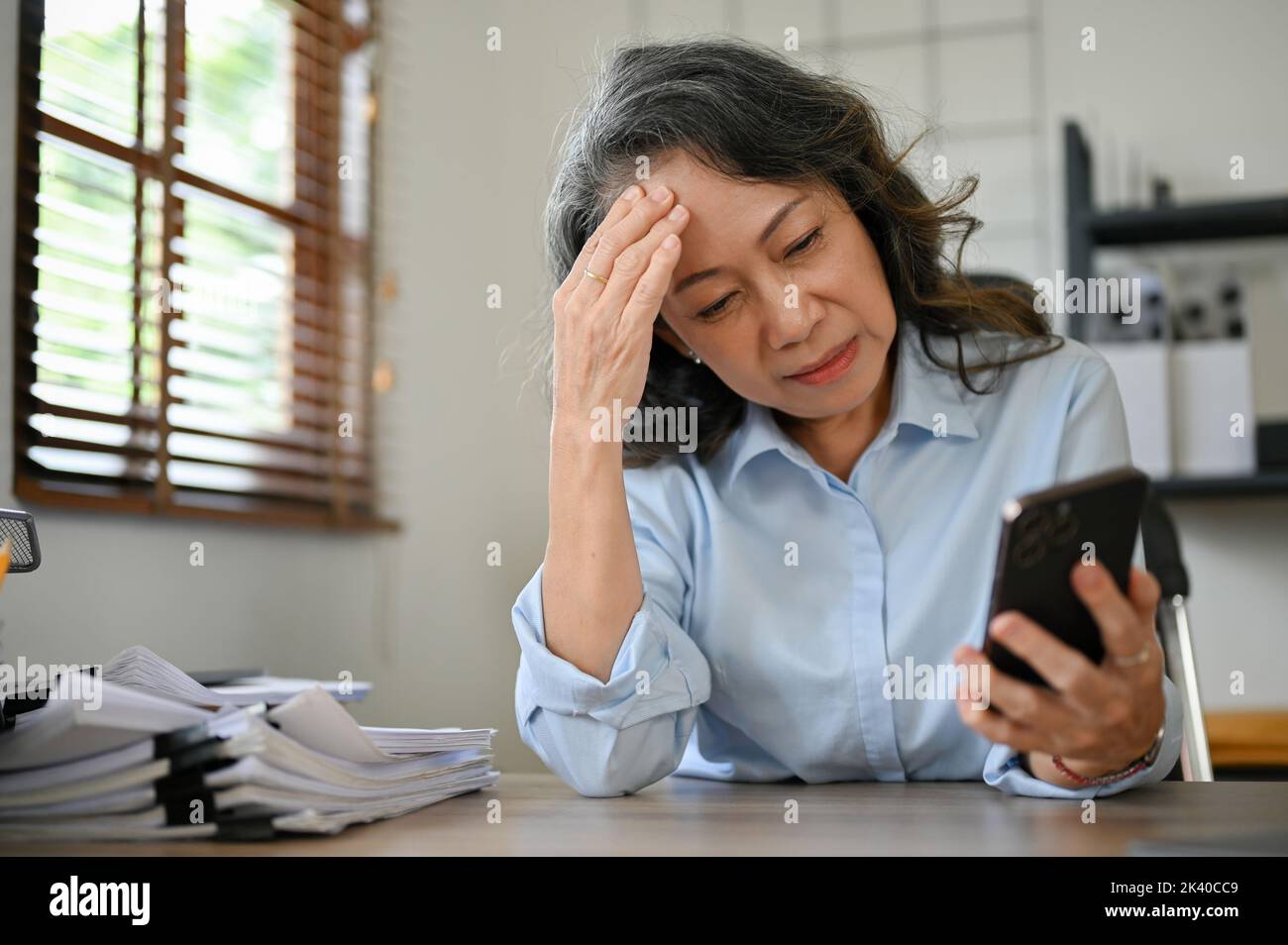 Stressed and sad Asian aged businesswoman or senior female manager at ...