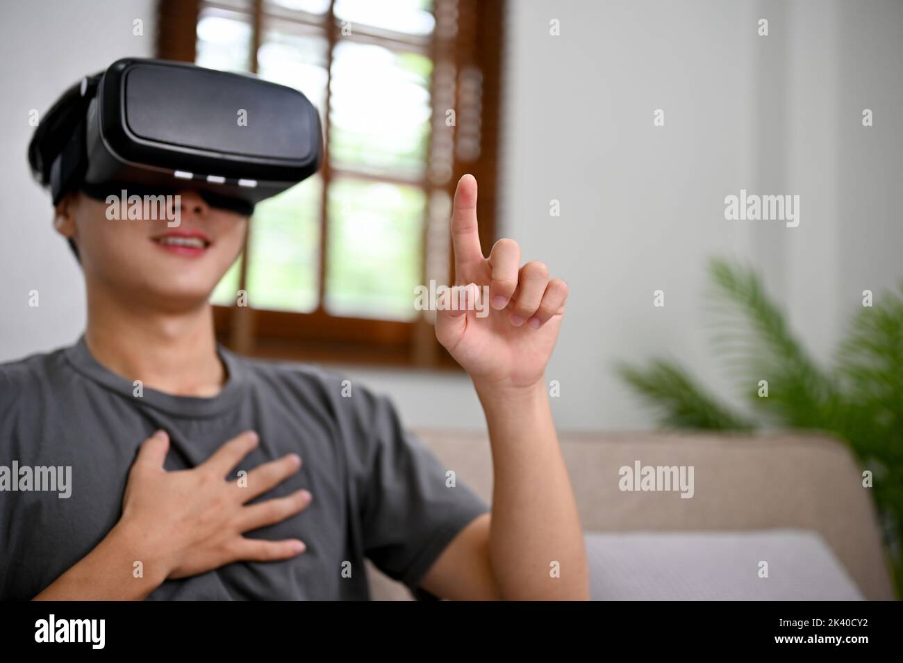 Excited and joyful young Asian man wearing VR goggles, playing ...