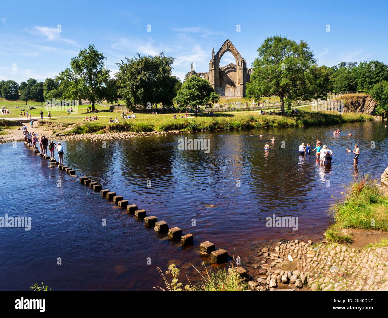 People crossing the stepping stones and paddling in the River Wharfe at ...
