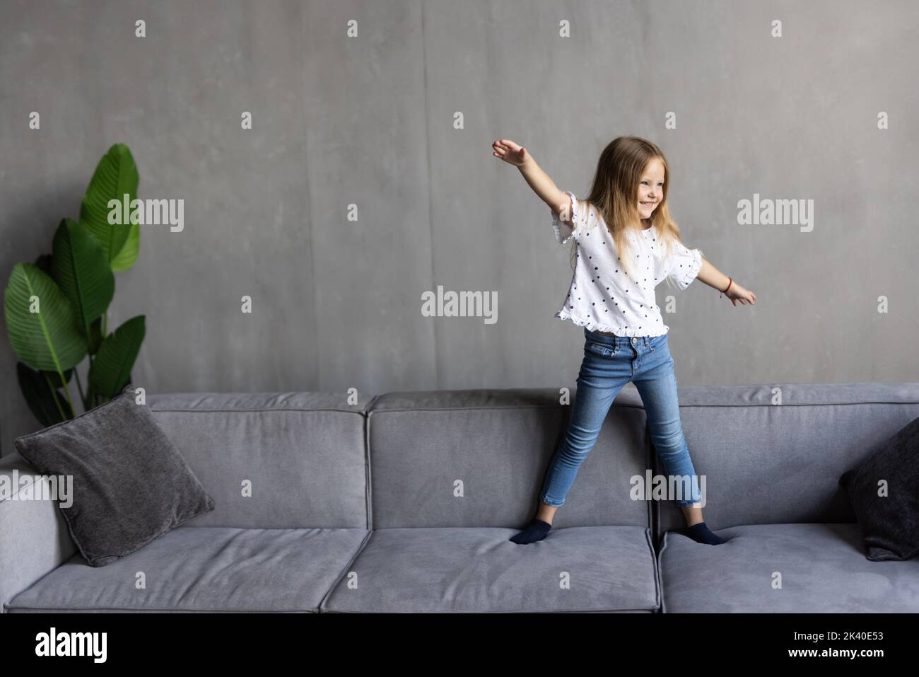 Adorable little girl jumping at home on sofa Stock Photo - Alamy
