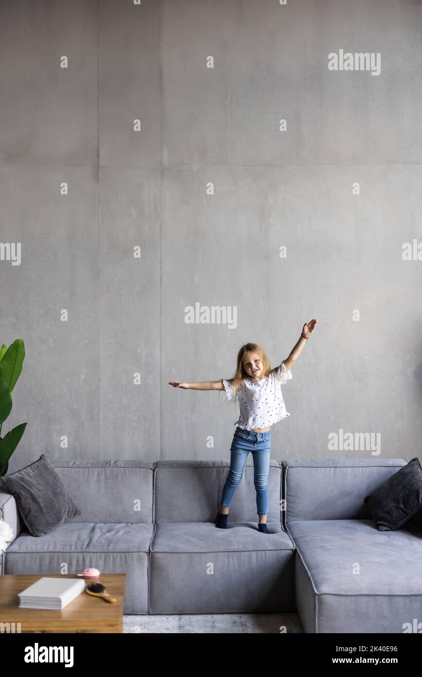 Adorable little girl jumping at home on sofa Stock Photo - Alamy