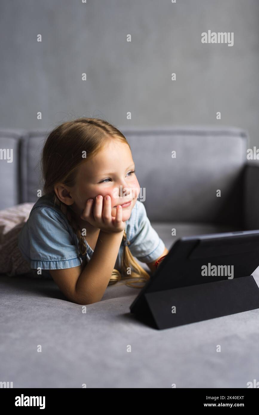 Focused cute preschooler girl watching movie, animated films, cartoons ...