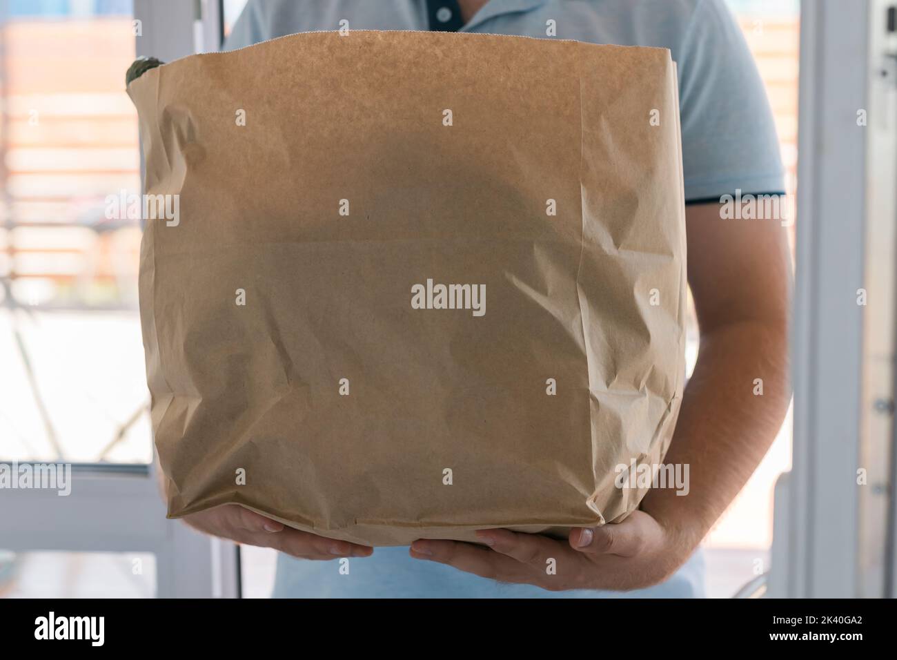 Deliver man wearing face mask in blue uniform handling bag of food give ...