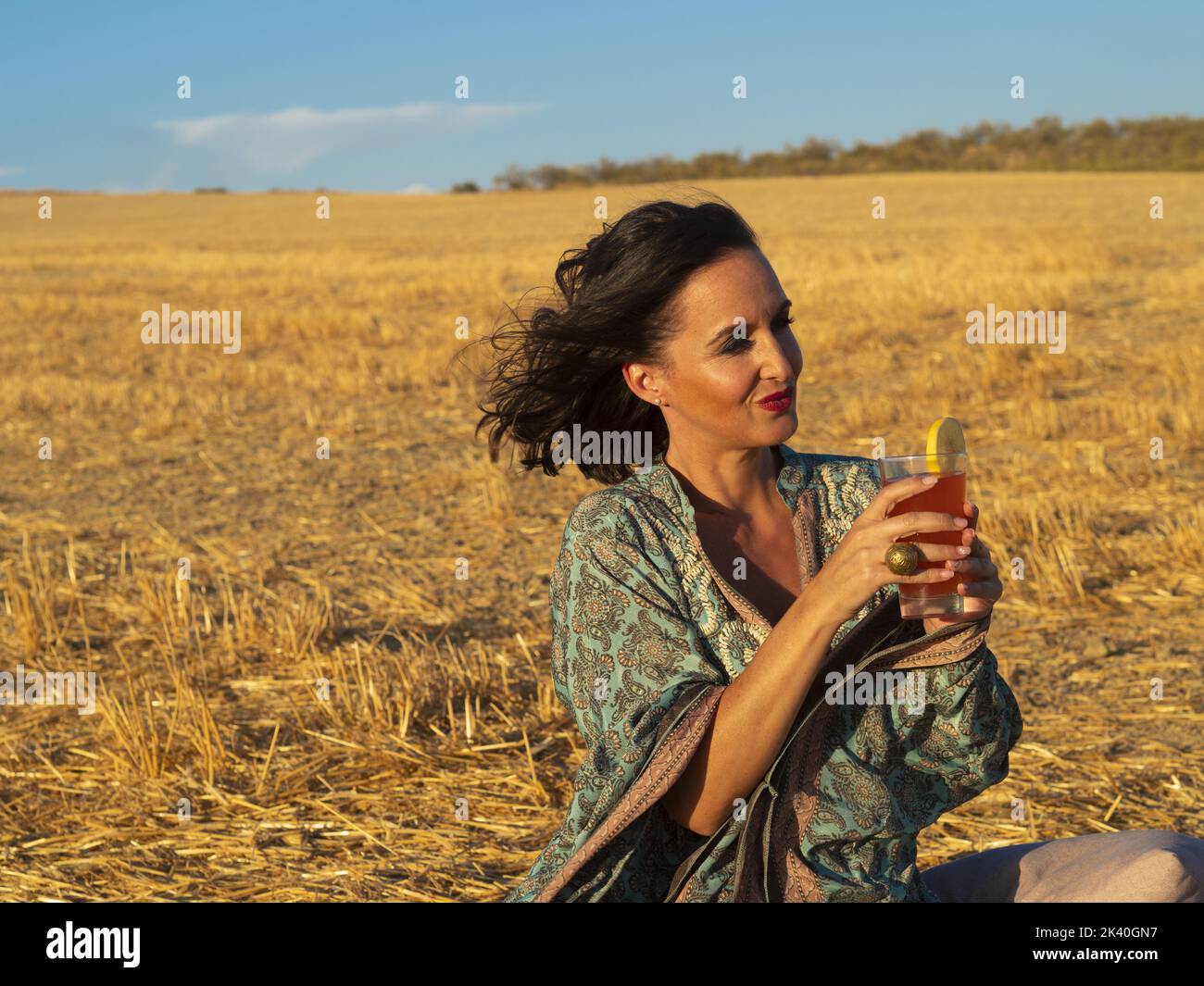 Content adult woman in boho dress holding glass of cool beverage ...