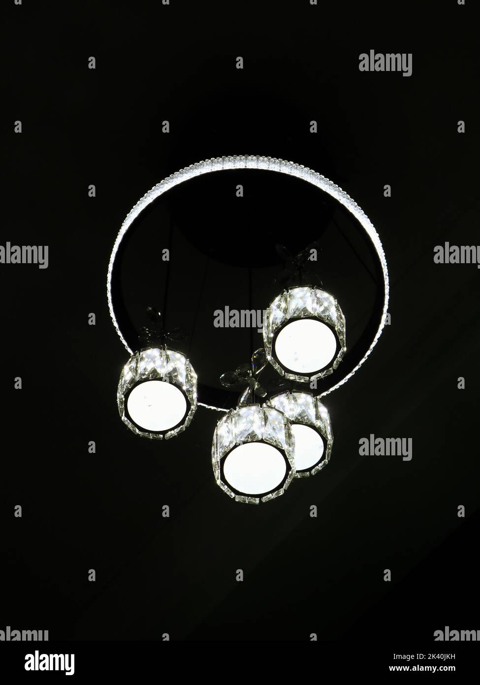 glowing round LED chandelier light on a black background in the ceiling ...