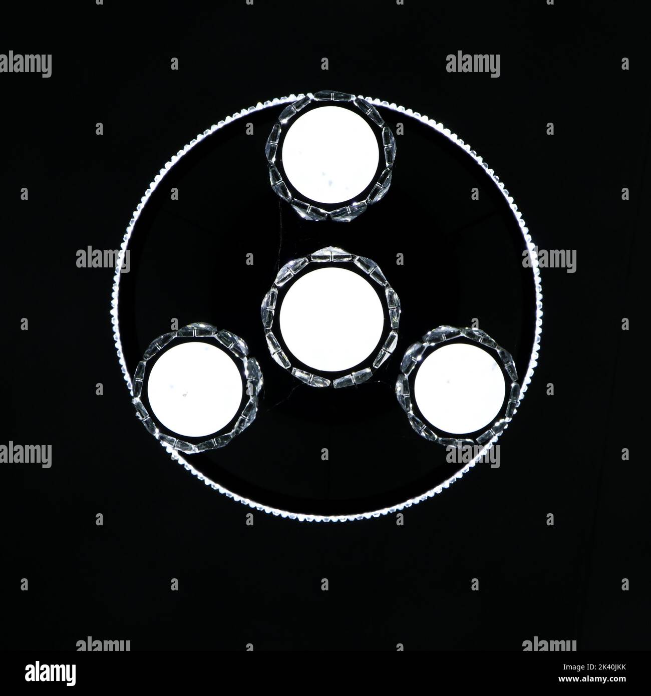 glowing round LED chandelier light on a black background in the ceiling ...