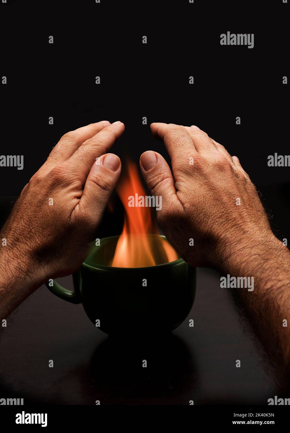 man's hands over cup with fire tocup with fire energy poverty Stock ...