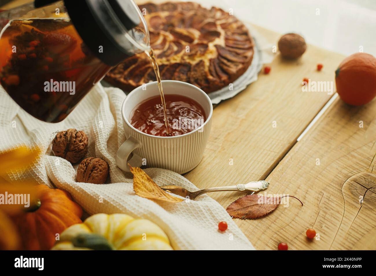 Pouring herbal tea in stylish cup on background of wooden table with ...