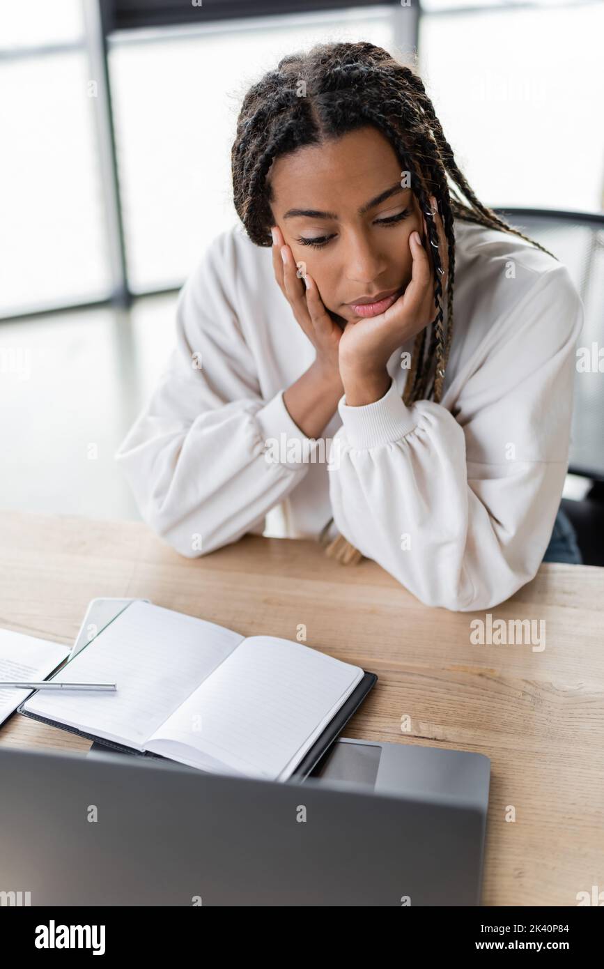 African american businesswoman looking at laptop near notebook with ...