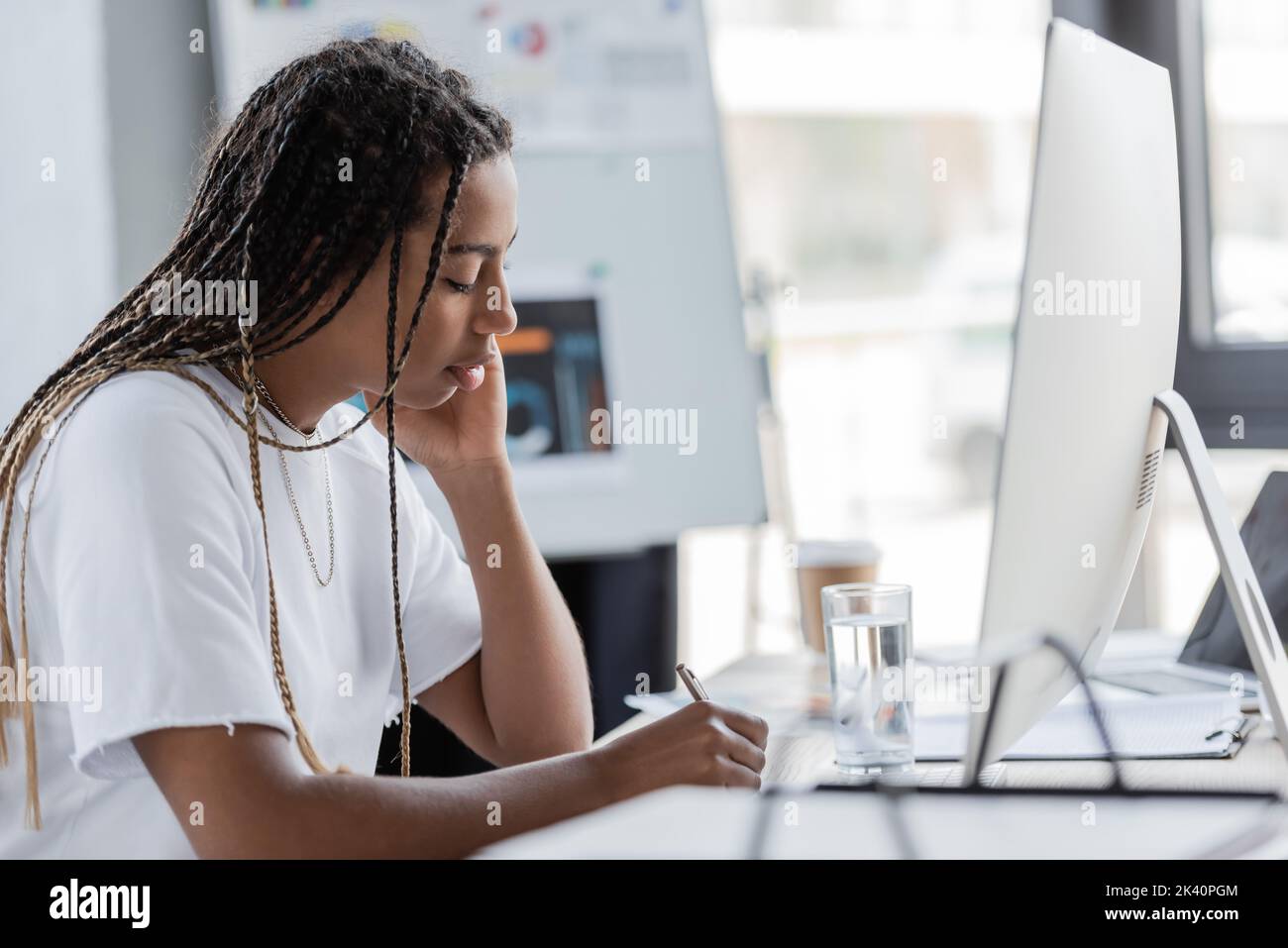 African american businesswoman in t-shirt writing near computer and ...