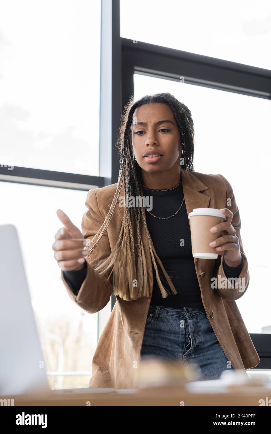 African american businesswoman holding coffee to go and pointing with ...