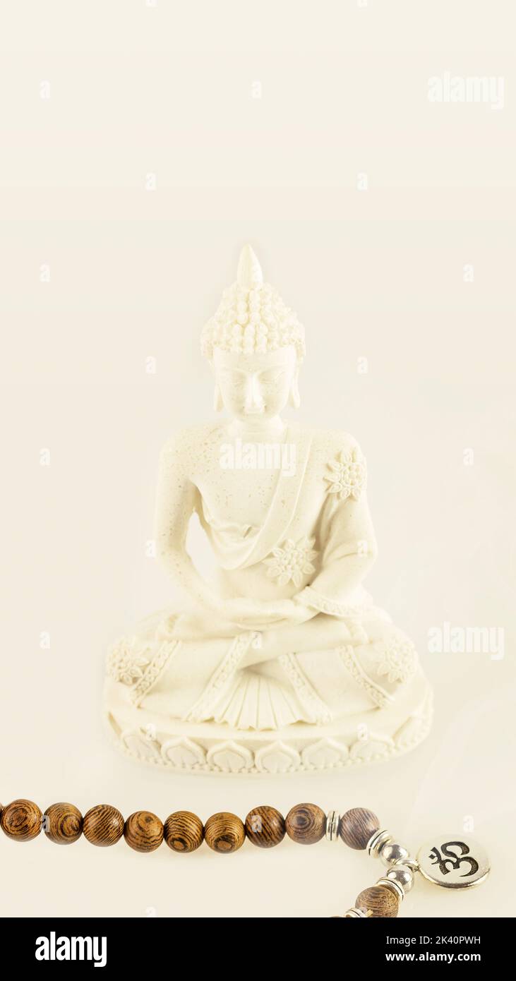 Buddha statue and prayer beads on a light background with copy space ...