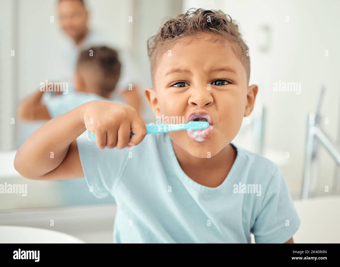 Portrait of learning child cleaning and brushing teeth in home bathroom ...
