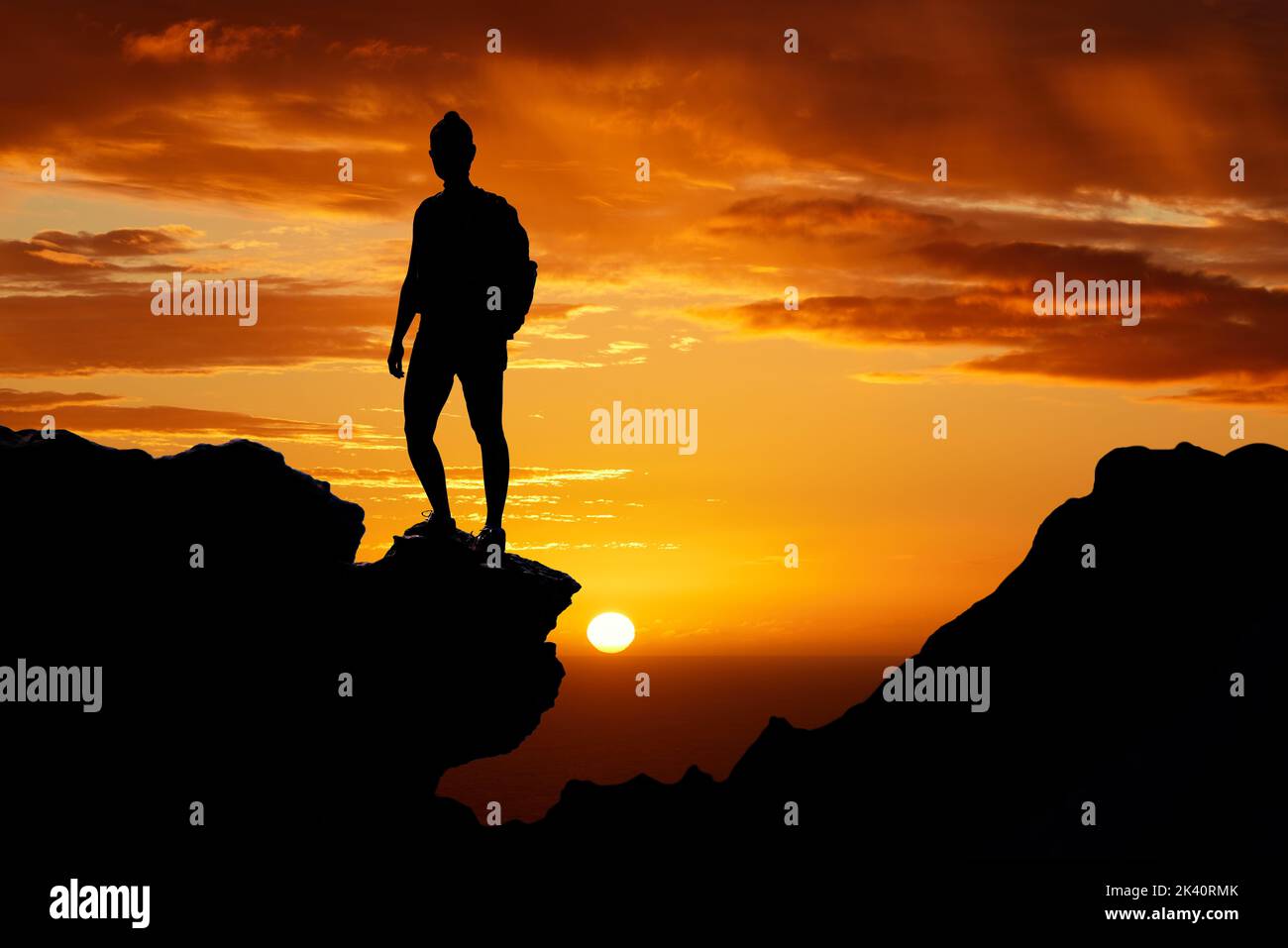 Sunset, hiking and silhouette of a man on top of the mountain during an ...