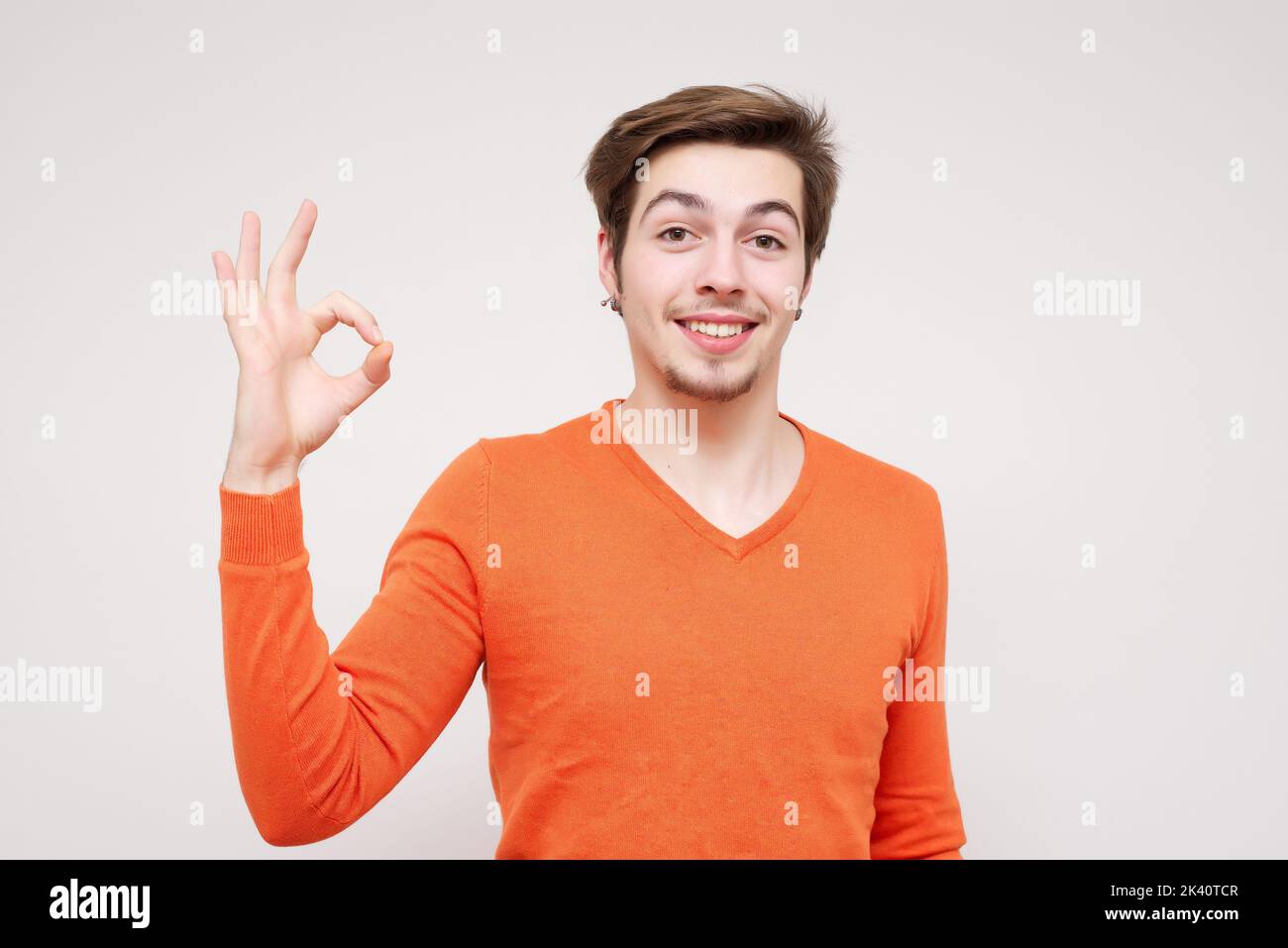 Portrait of a young man showing ok sign with a large smile on his face ...