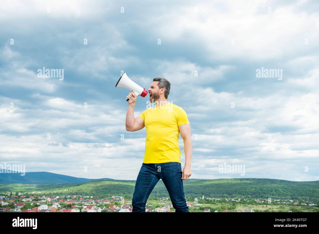 man in yellow shirt shout loud in megaphone on sky background Stock ...