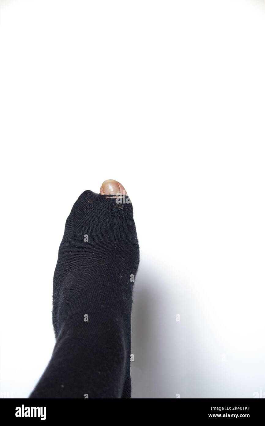 Hole in a black sock through which the big toe sticks out. White ...