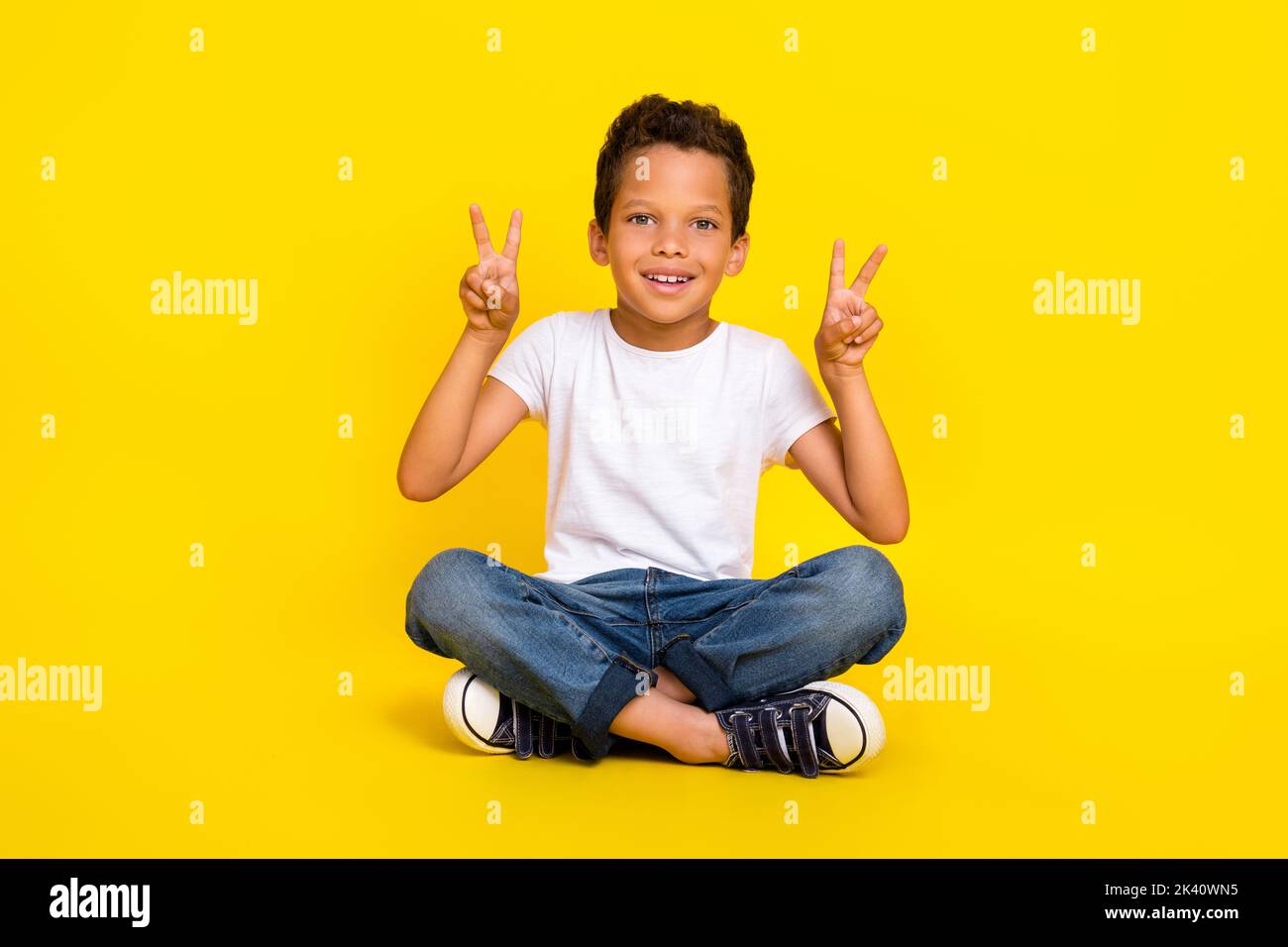 Full body photo of small boy sit show v-sign wear t-shirt jeans boots ...
