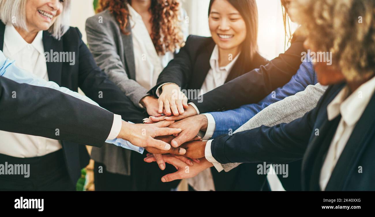 Multiracial business people celebrating together stacking hands inside ...