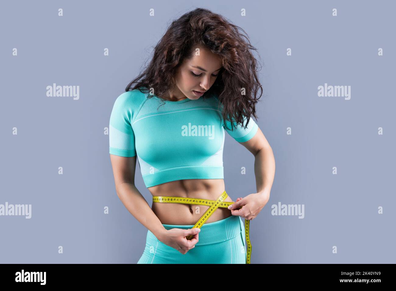 Fit woman measuring waist size with tape measure studio. Sportswoman ...