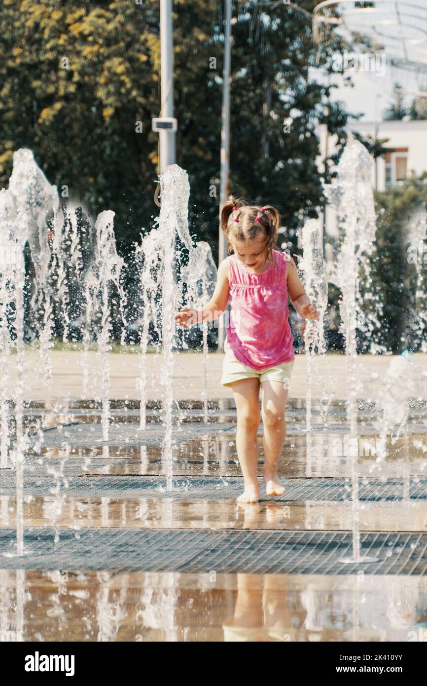 little girl playing with small fountains on the urban plaza Stock Photo ...