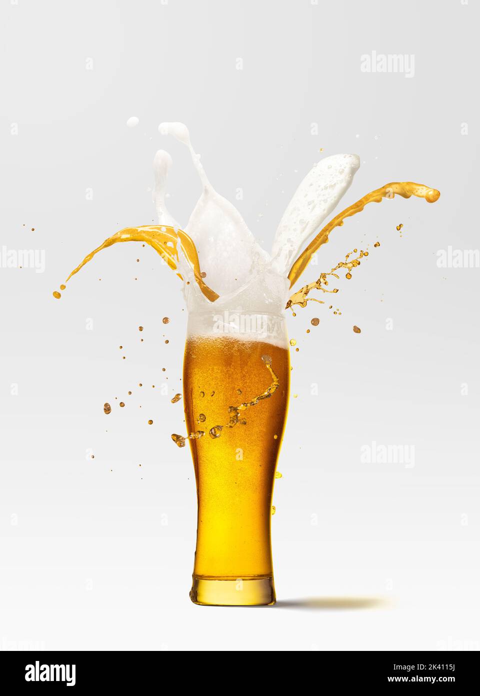 Foam and beer splashes from full glass of frothy light lager beer ...