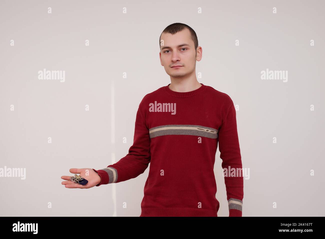 One young man caucasian holding keys portrait in studio white ...