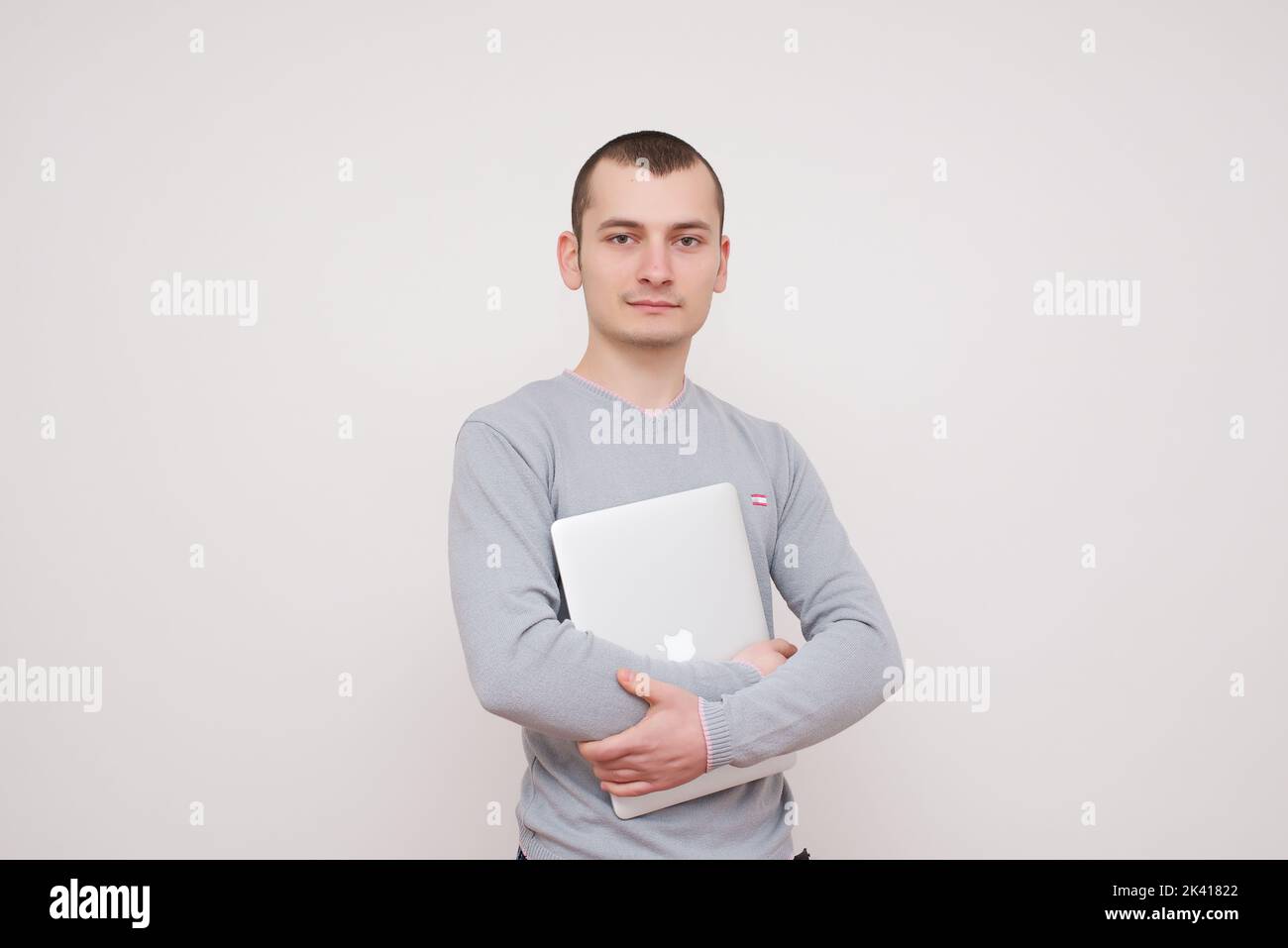 Confident young man with laptop standing over white background. stock ...