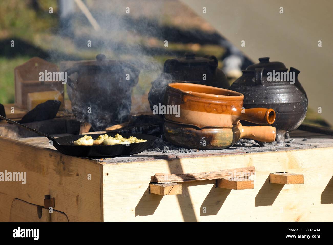 Medieval cooking place, set up with different pots and a burning and ...