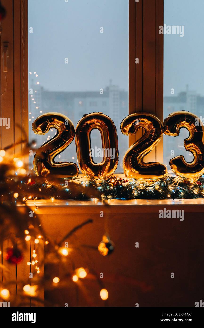 2023 golden foil balloons on blue window sill. Celebrating holidays at ...