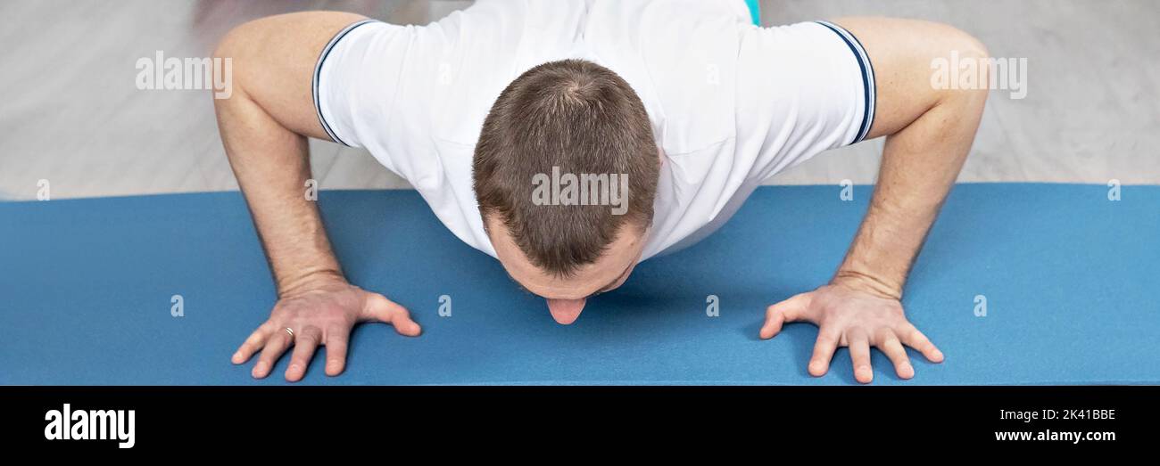 A strong, healthy man with muscles, training at home in the plank ...