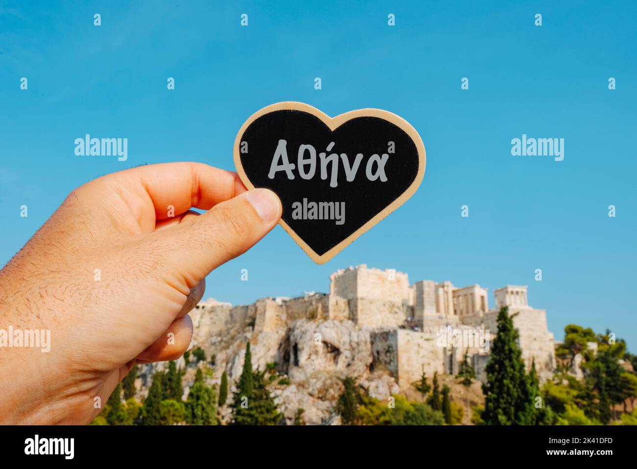 closeup of the hand of a man holding a heart-shaped sign with the word ...