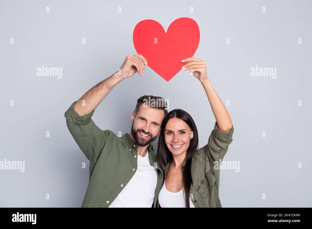Portrait of attractive cheerful couple hugging holding heart card shape ...