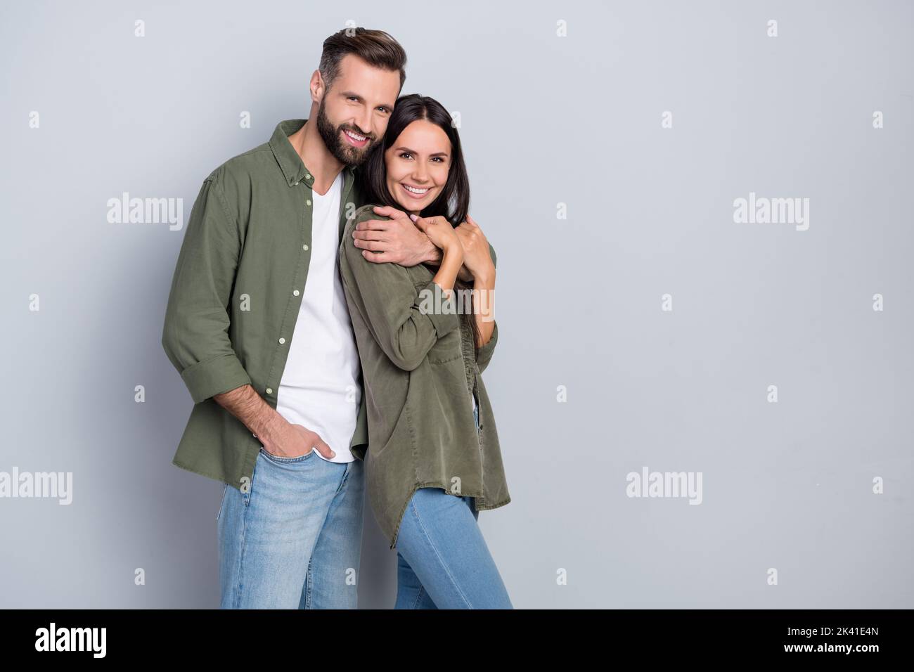 Portrait of attractive tender cute sweet cheerful couple cuddling copy space isolated over grey ...