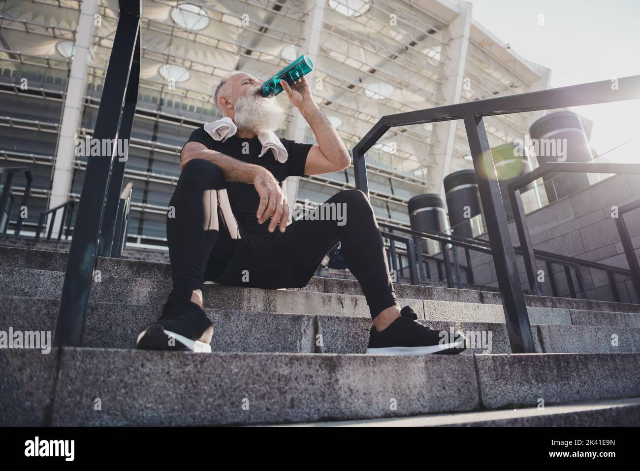 Portrait of attractive grey-haired retired man working out drinking ...