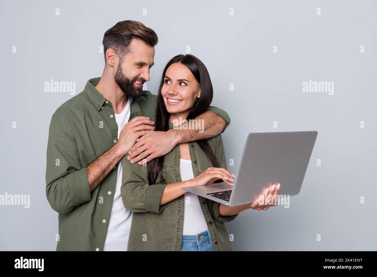 Portrait of attractive tender cheerful couple cuddling using laptop ...