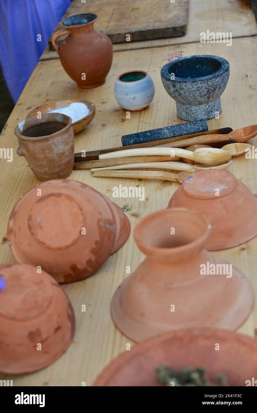 Plates, pots and artifacts made of clay on the table with spoons and ...