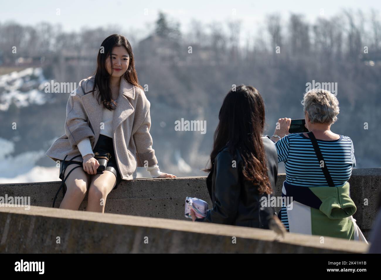 Happy, smiling woman posing for a pictures in front of Niagara Falls in ...