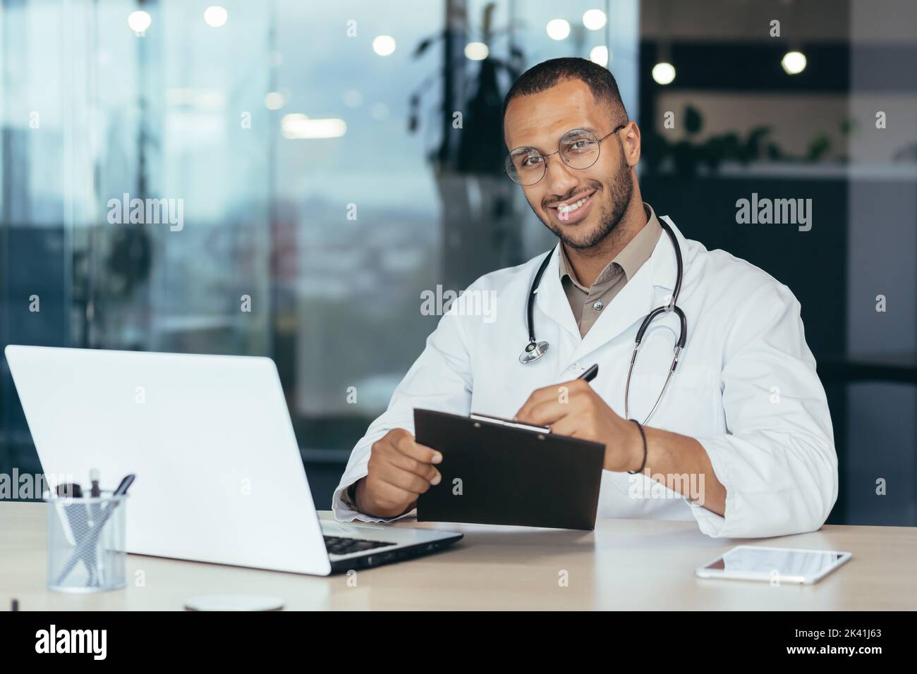 Portrait of successful male doctor, hispanic smiling and looking at ...
